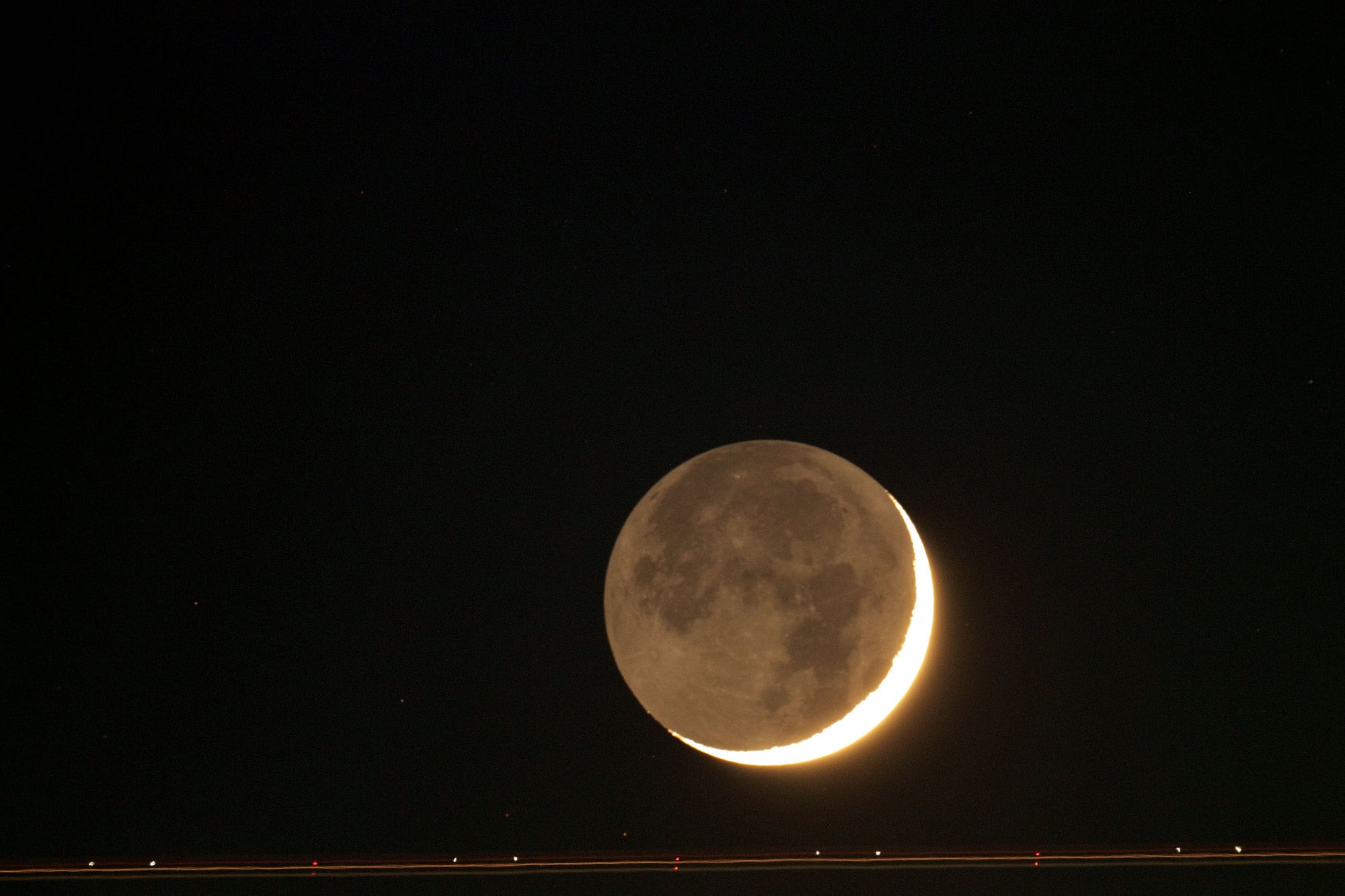 Mond mit sekundärem Mondlicht und Flugzeugspur - Spektrum der Wissenschaft